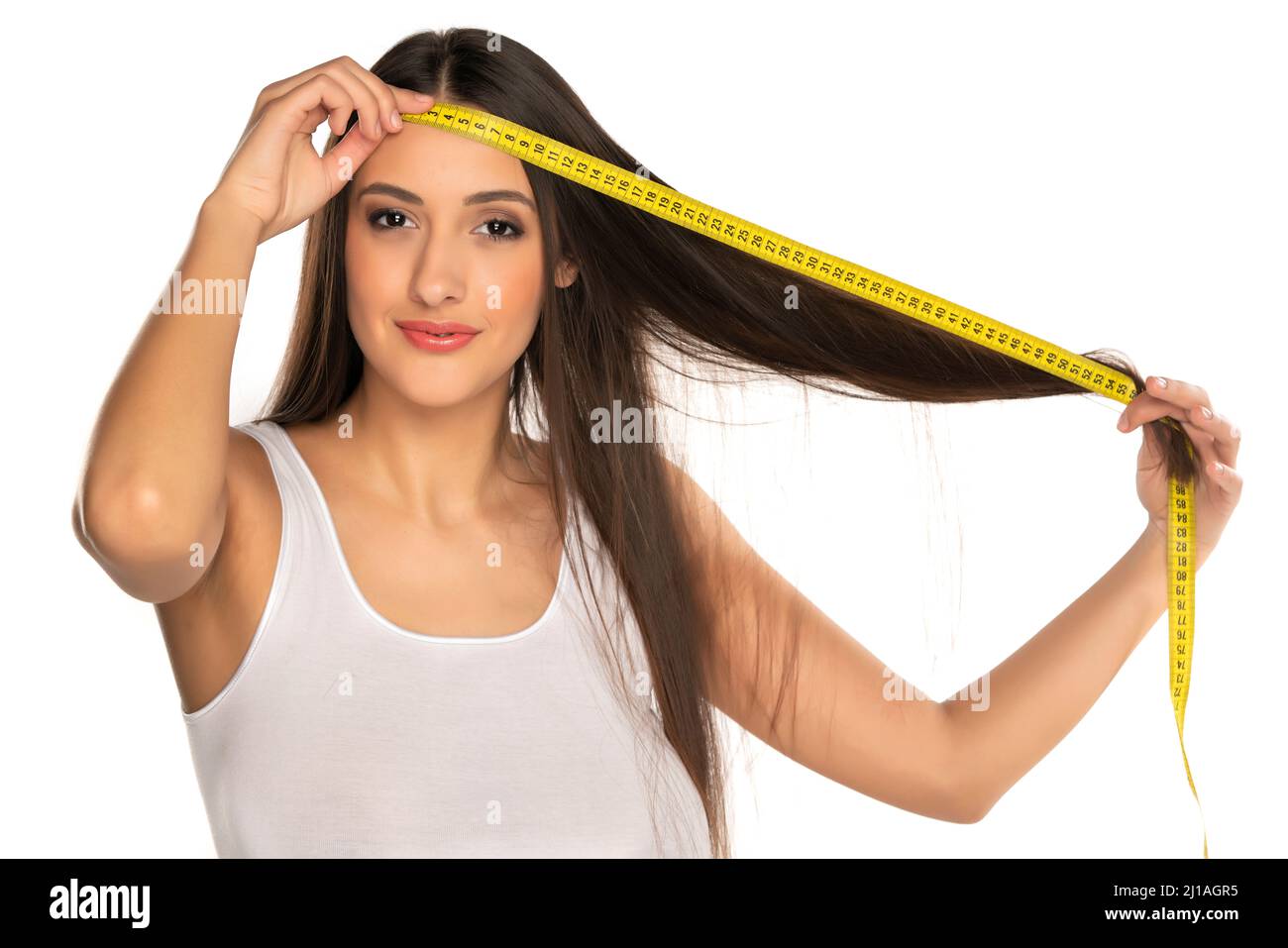 a young happy woman shows the length of her hair with a measuring tape ...