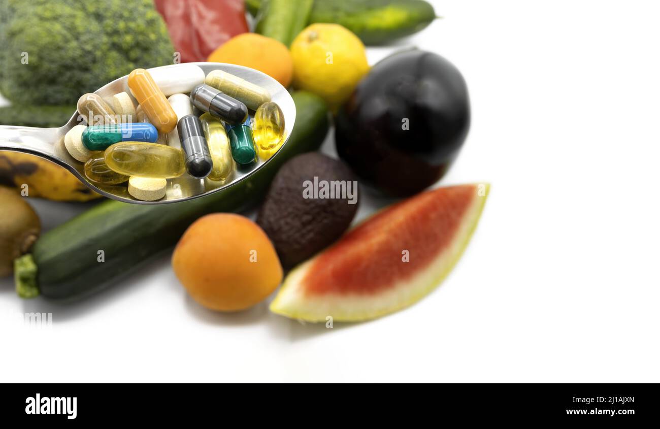 Capsules and pills of nutritional supplements and fresh vegetables and ...
