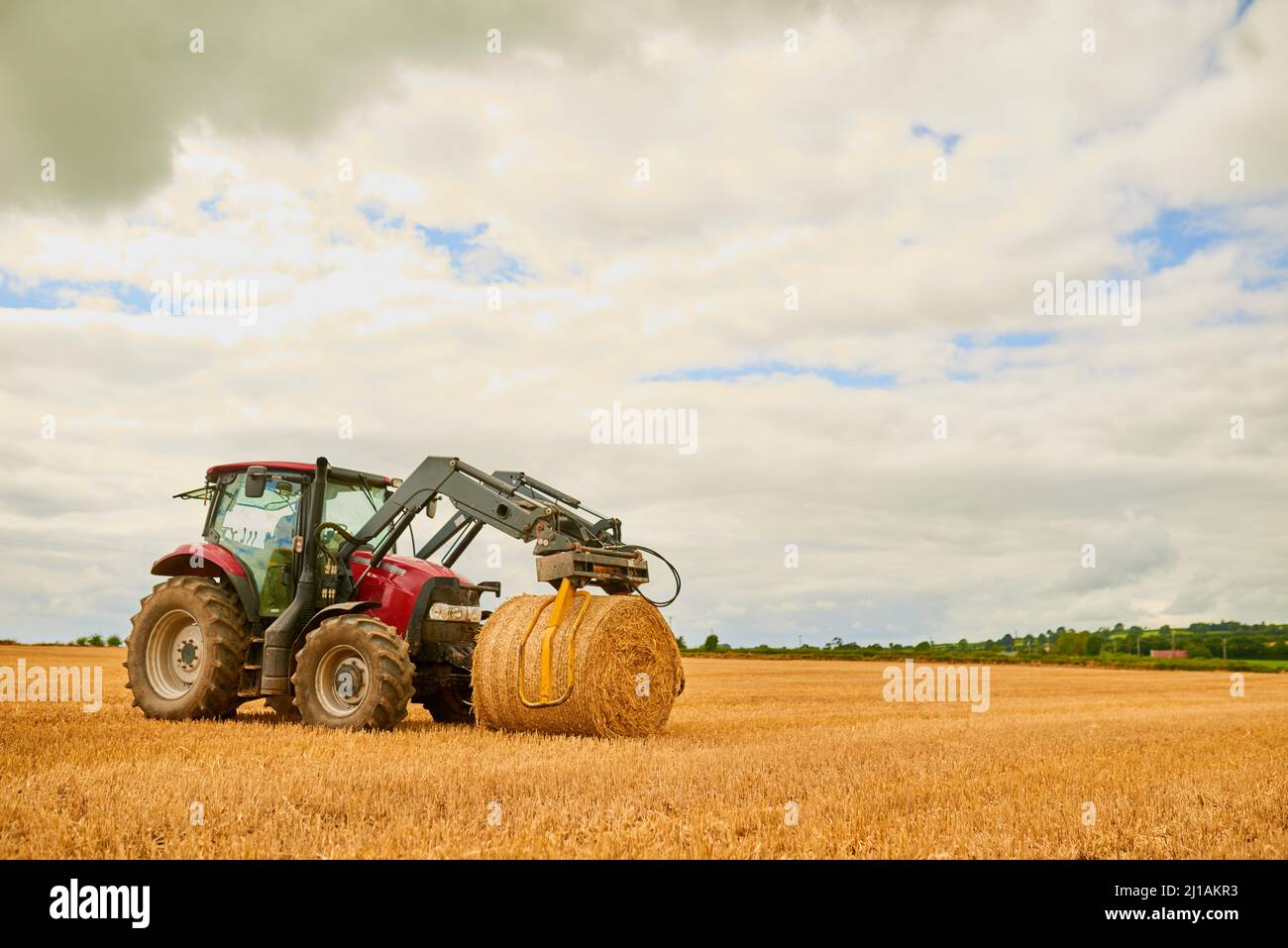 His farm is well-kept. Shot of a farmer stacking hale bales with a ...