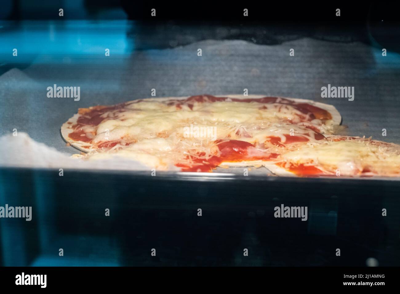 Cheese pizza with strange shape being cooked on a domestic oven Stock ...
