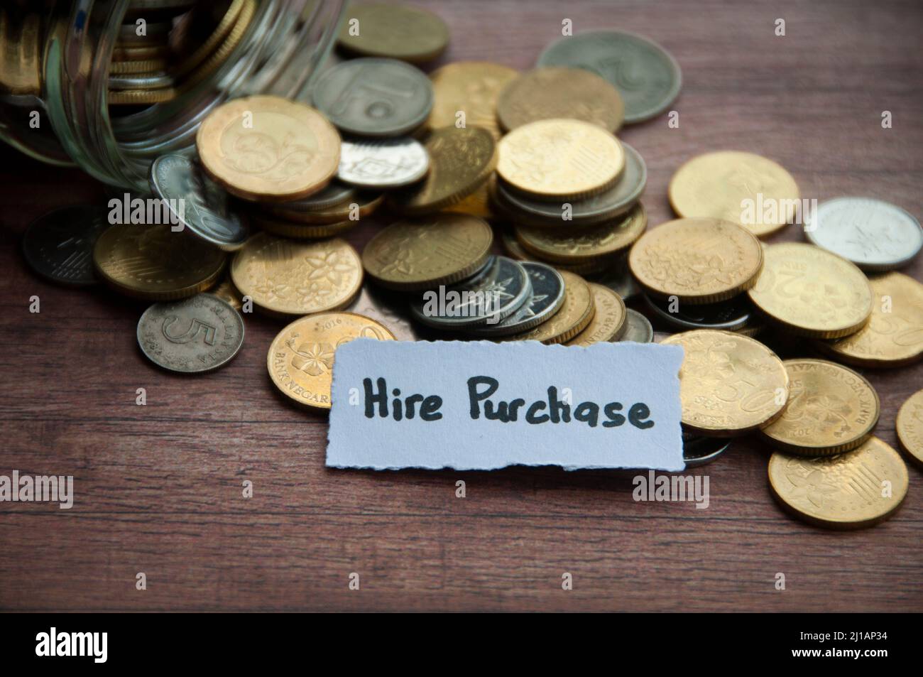 Hire purchase text on torn paper with jar, coins, and wooden table ...