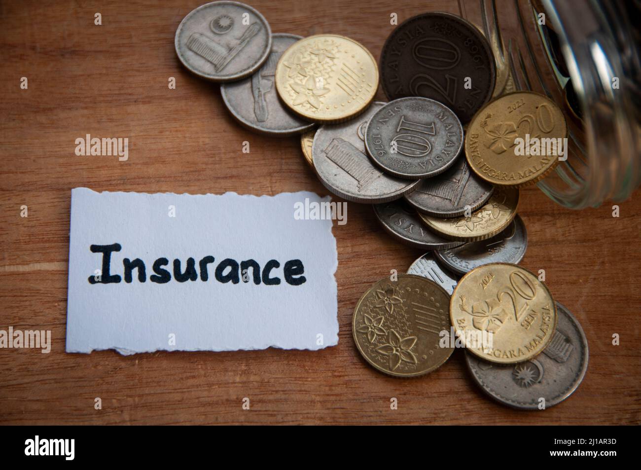 Insurance text on torn paper with jar, coins, and wooden table ...