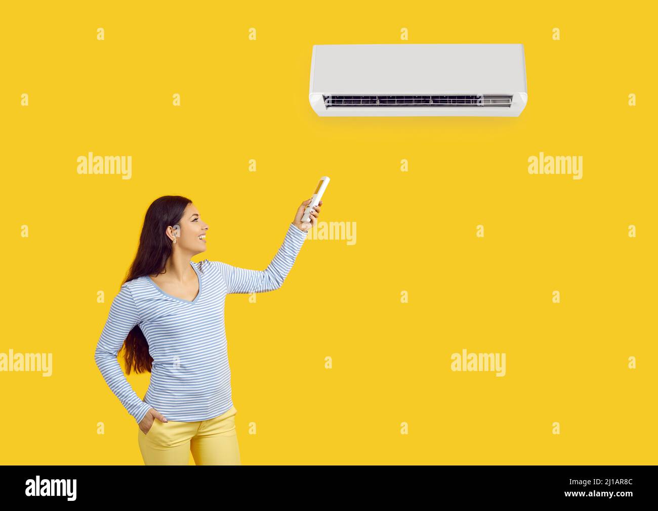 Woman with remote control adjusts comfortable temperature on air ...