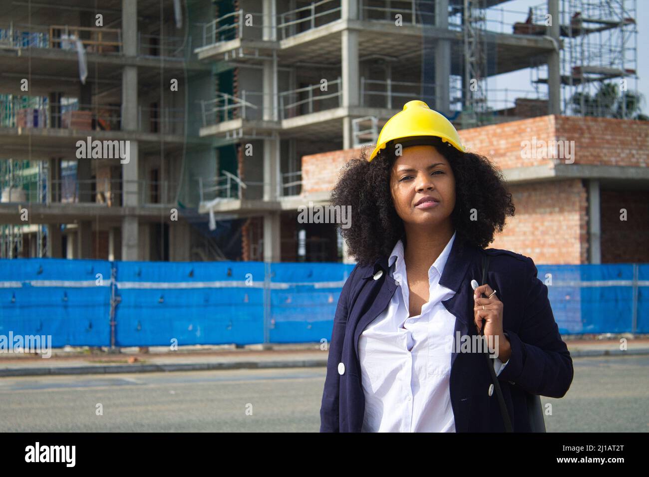 An African-American black woman construction manager in yellow hardhat ...