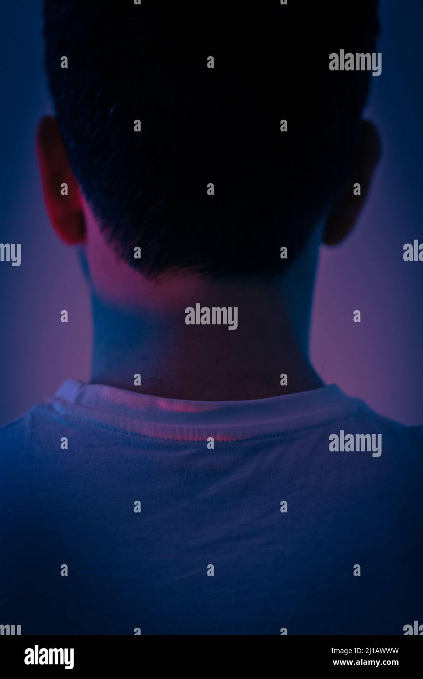 A vertical shot of a back view of a male with white t-shirt in a studio ...