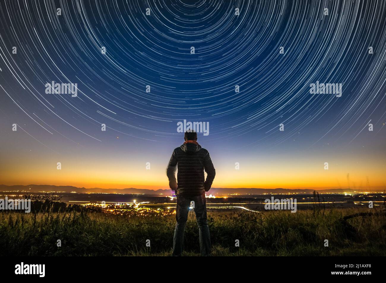A man standing in the field with stars captured with long exposure ...