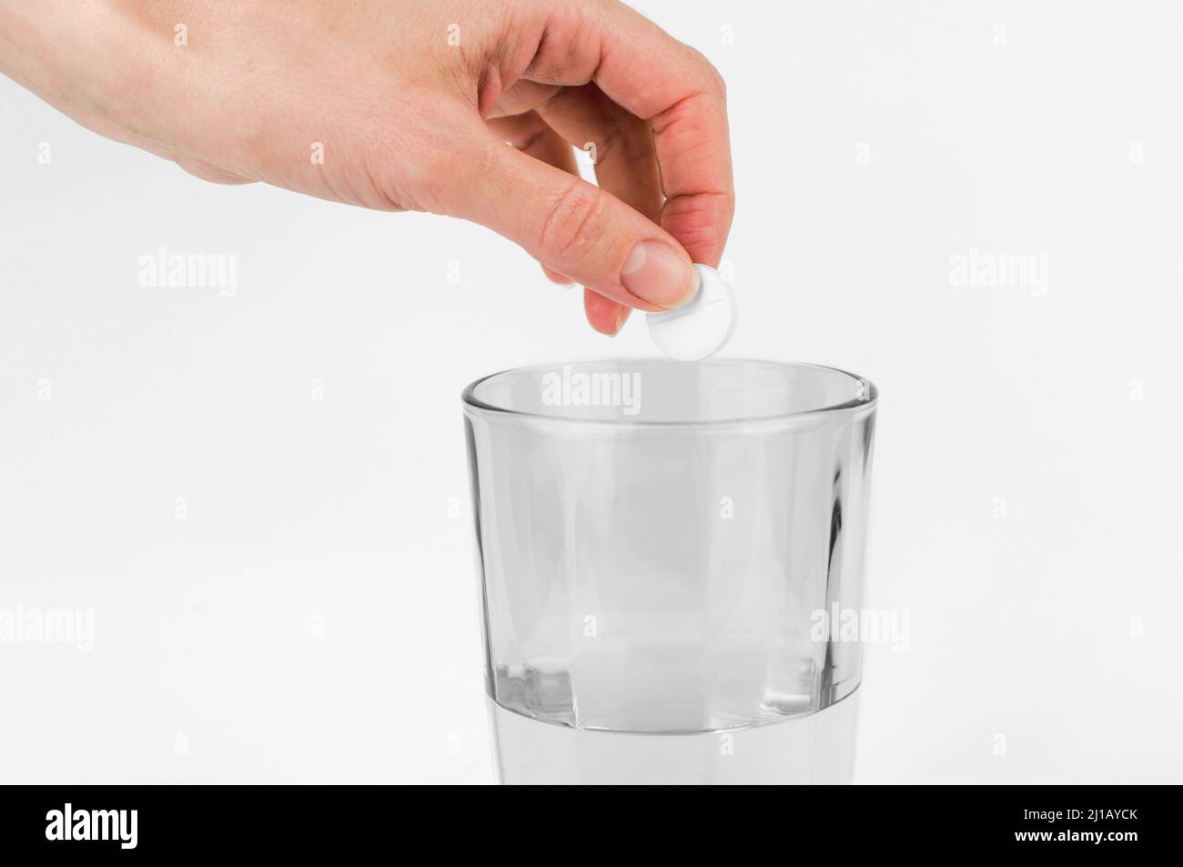 A woman's hand puts a soluble tablet in a glass, close-up, white ...