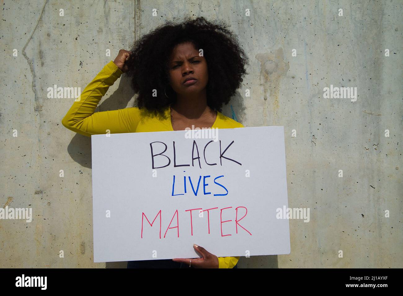 An angry african-american woman with raised fist holds up a banner ...
