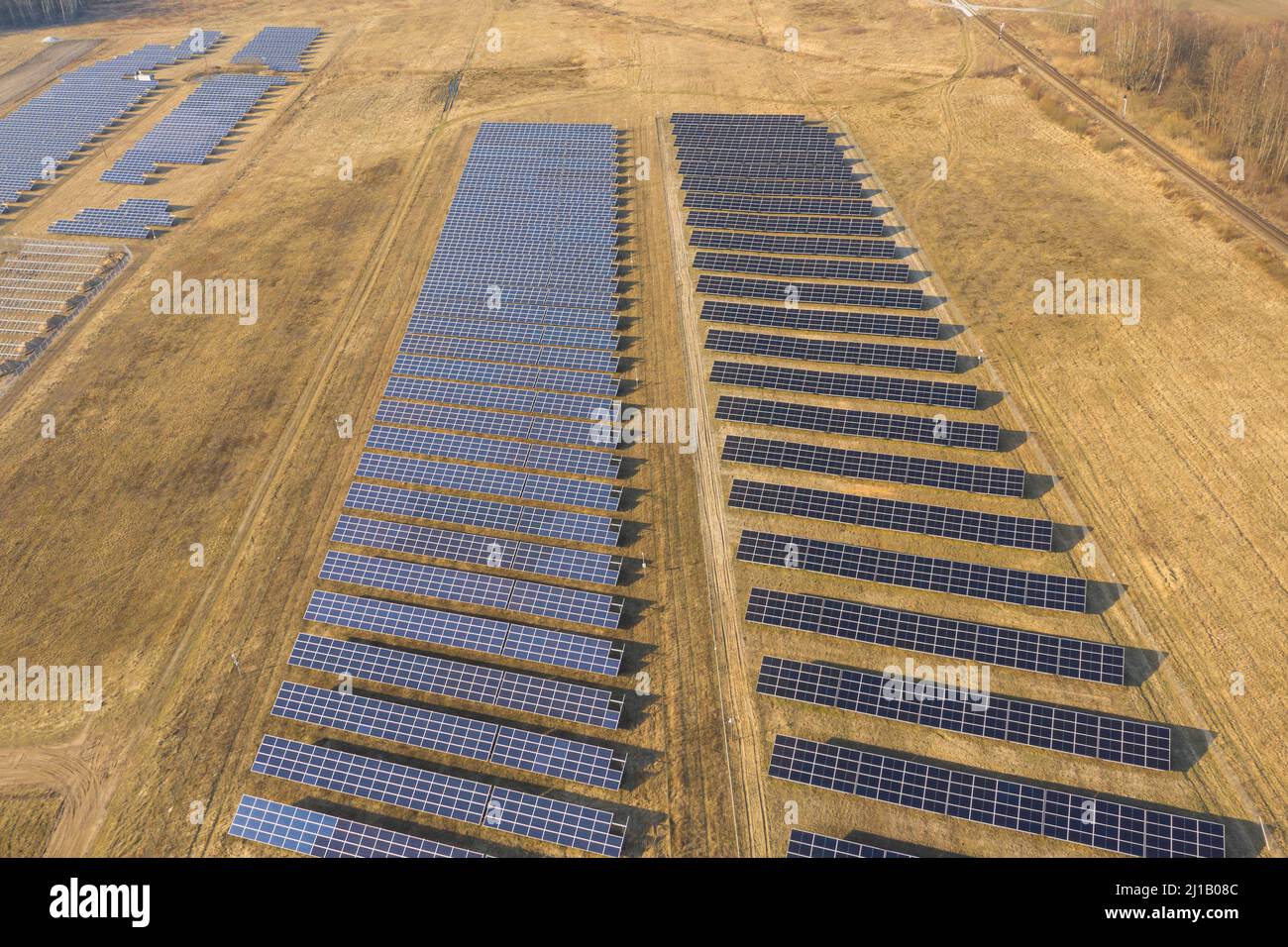 Flat, level ground covered in rows of solar panels. It's a sunny day ...