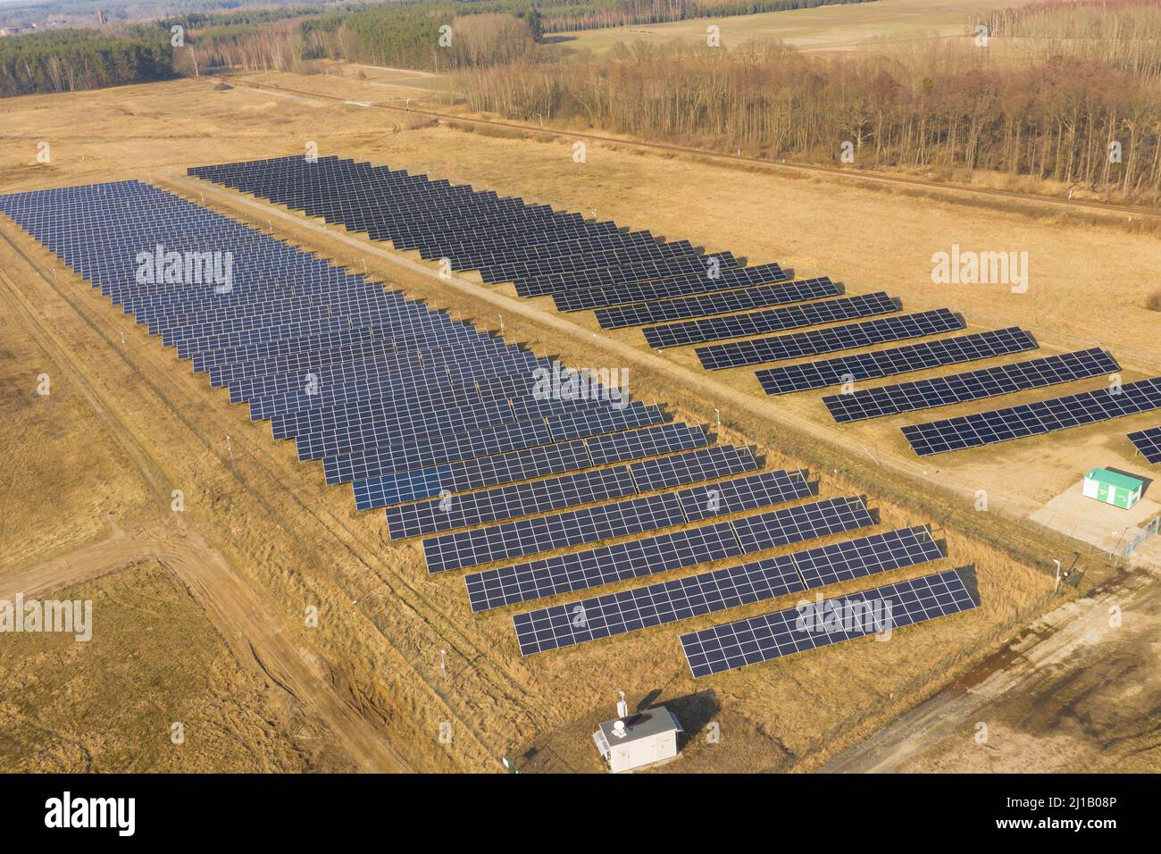 Flat, level ground covered in rows of solar panels. It's a sunny day ...