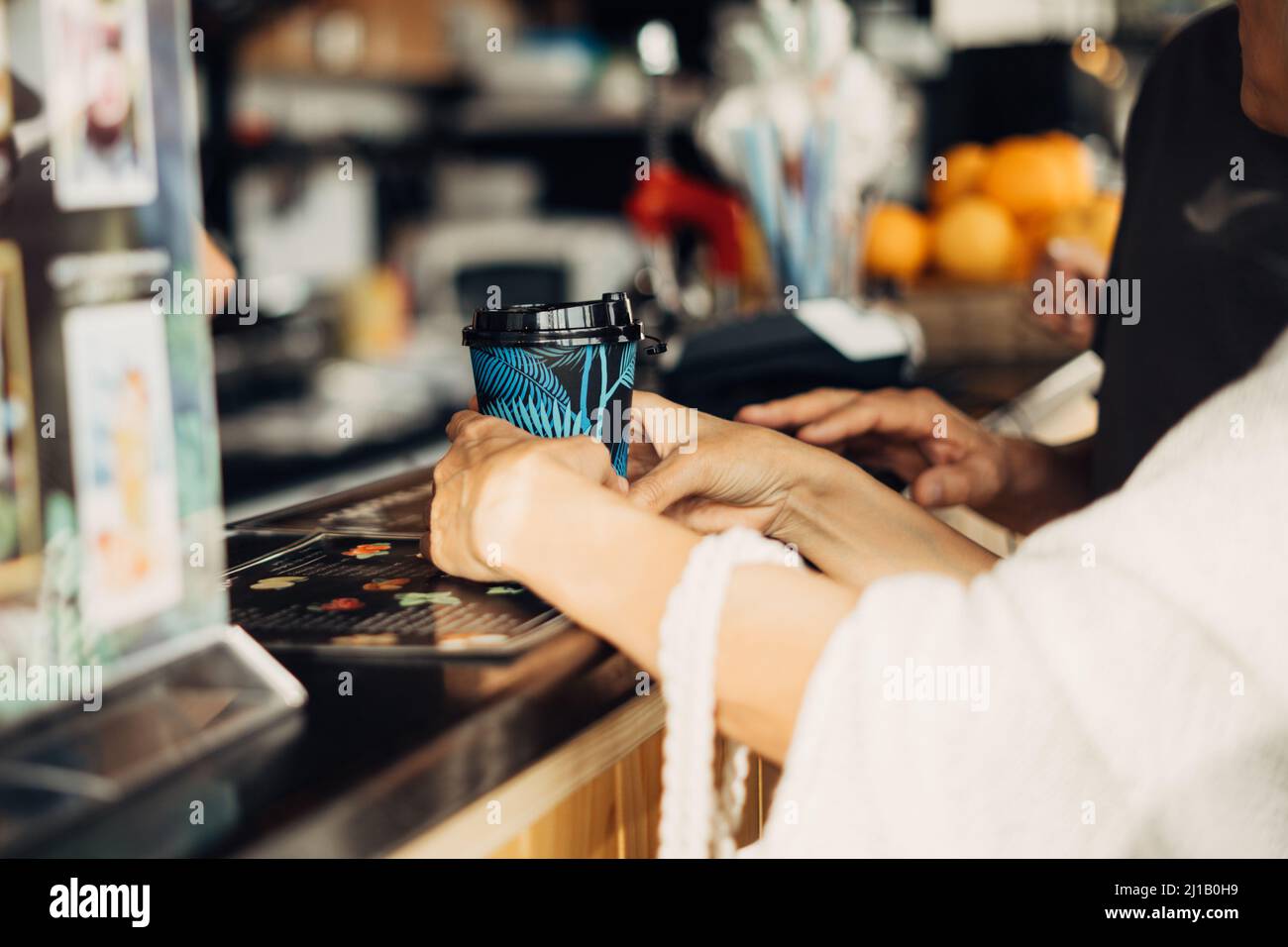 Cropped of woman's hands holding paper coffee cup on bar counter at ...
