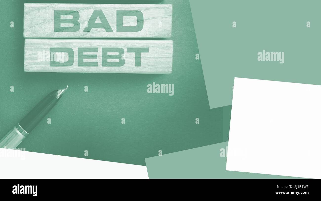 Bad debt on wooden blocks and luxury pen on dark grey background ...
