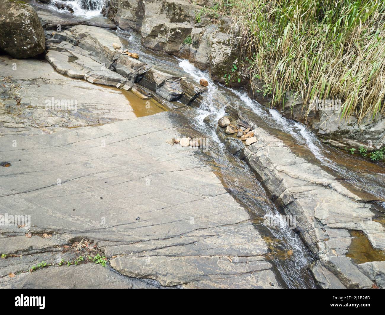 stream flows through rocks, narrow river or flow of water on a rocky ...