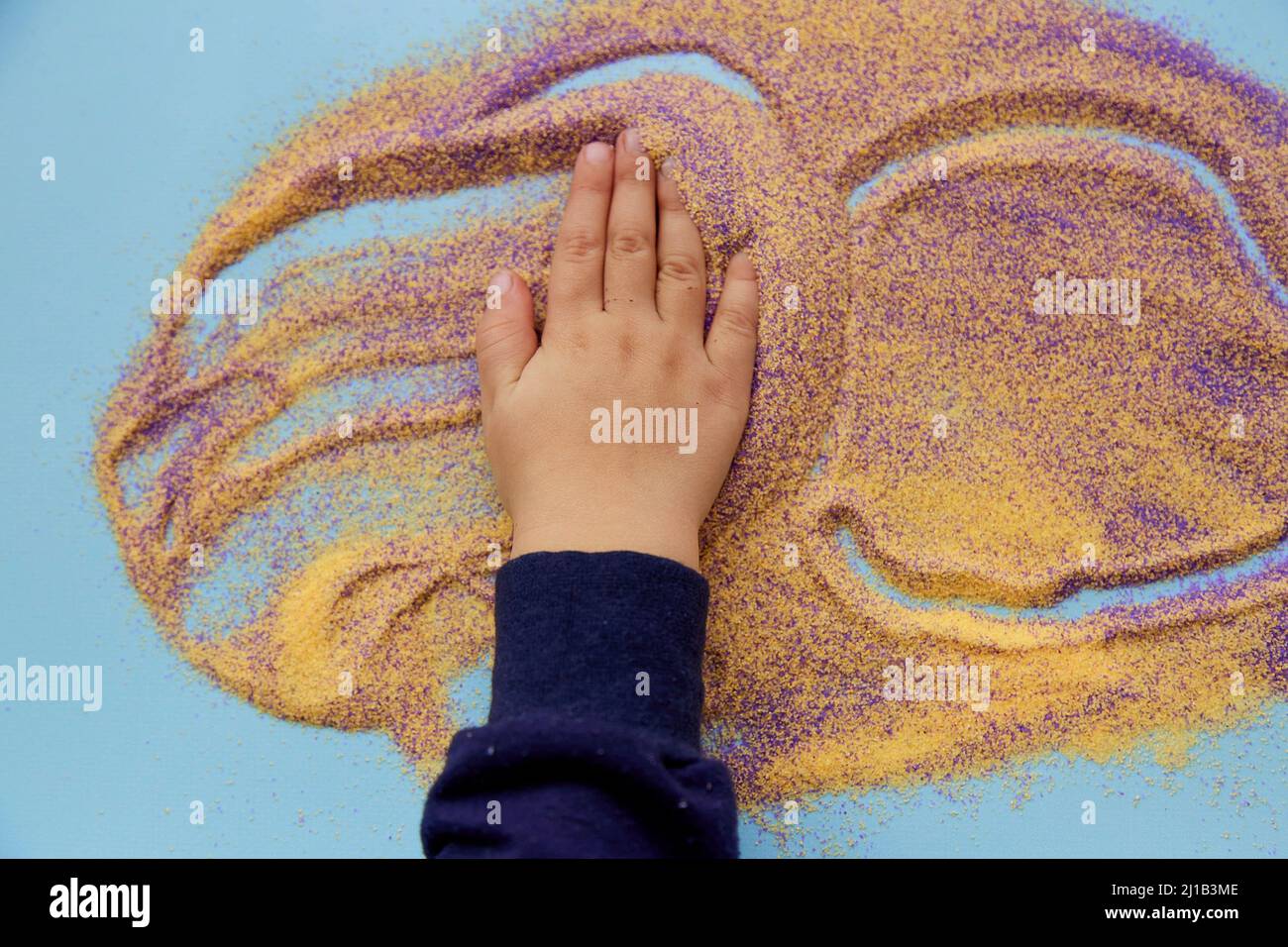 Baby hands plays with colorful sand. Child fine motor skills ...
