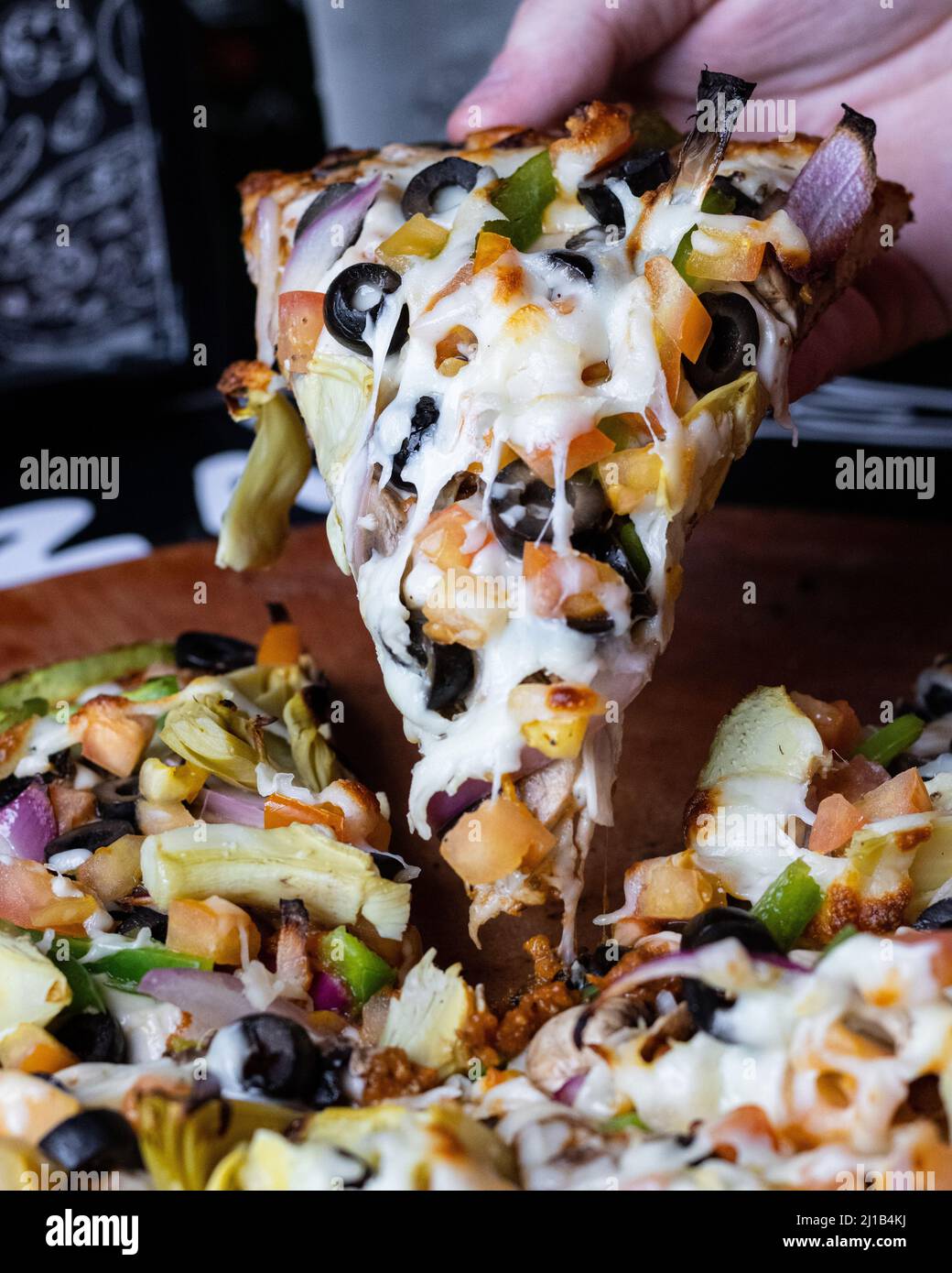 A vertical shot of a man holding a slice of pizza in his hand Stock ...