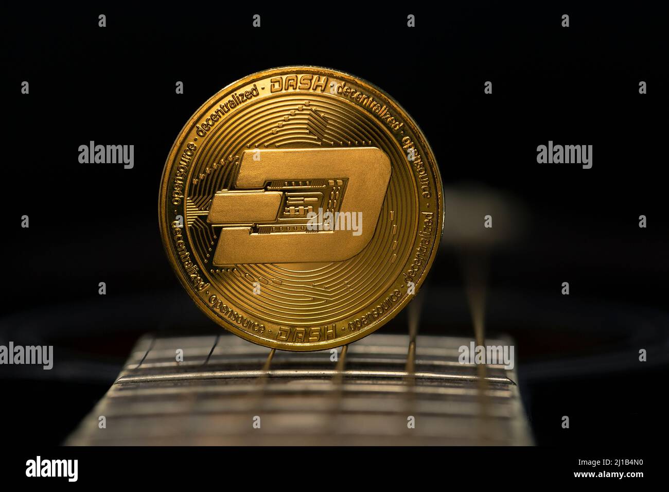Dash cryptocurrency physical coin placed on guitar strings in the black ...