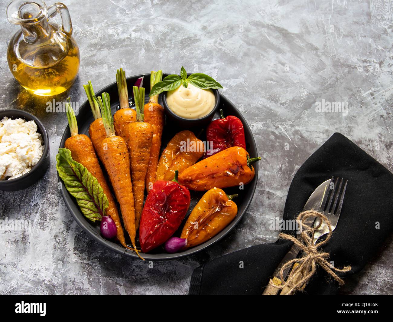 baked roast baby carrots, bell pepper in a plate, basil and spices ...