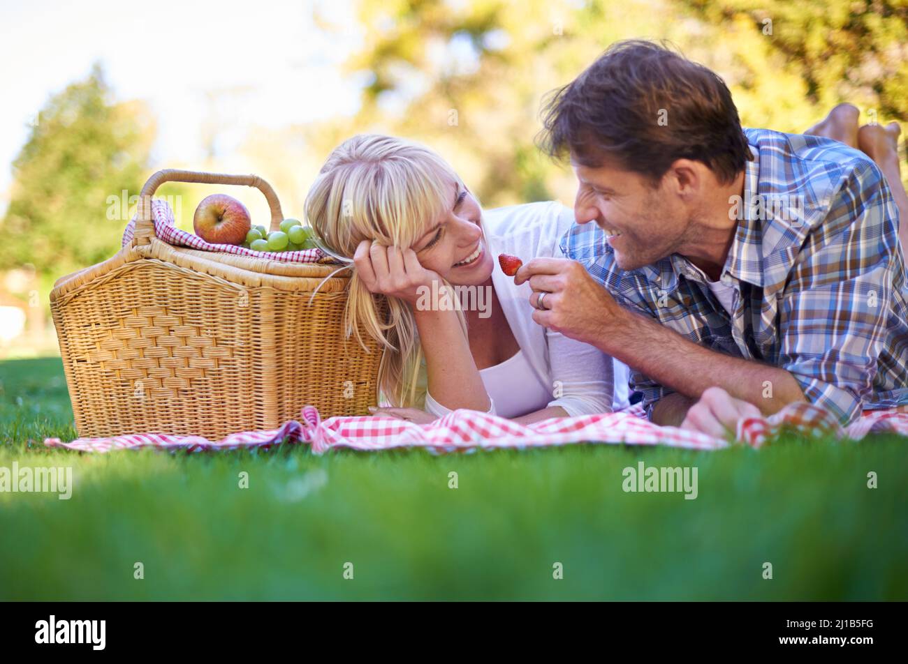 Open up. Shot of an affectionate couple enjoying a picnic in the sun ...