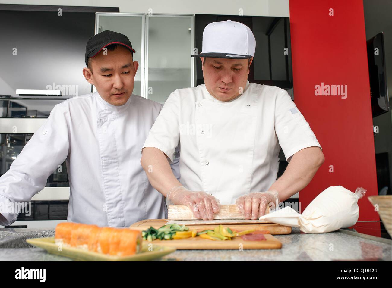Two happy young asian chefs dressed in white uniform preparing ...