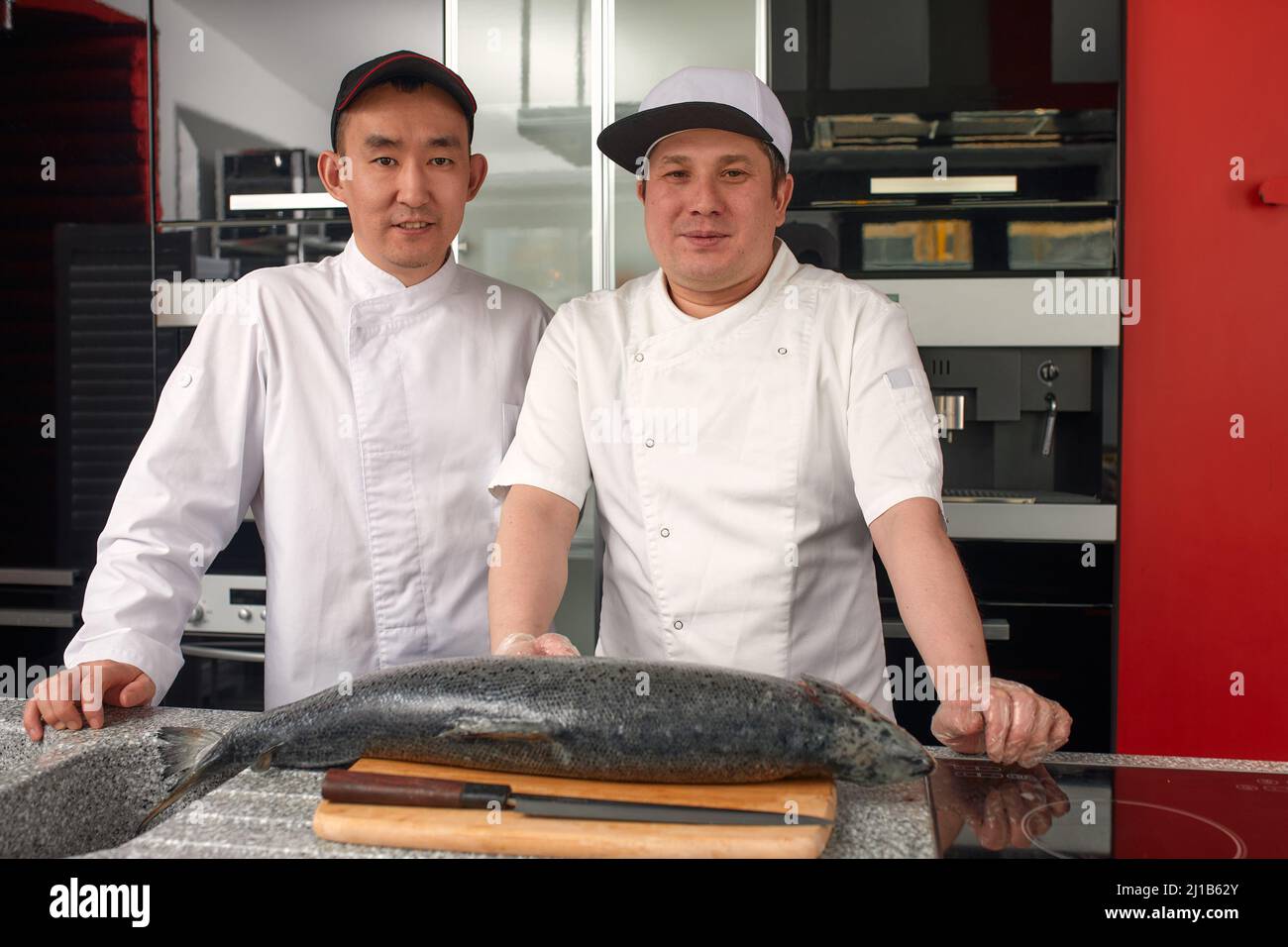Two happy young asian chefs dressed in white uniform preparing ...