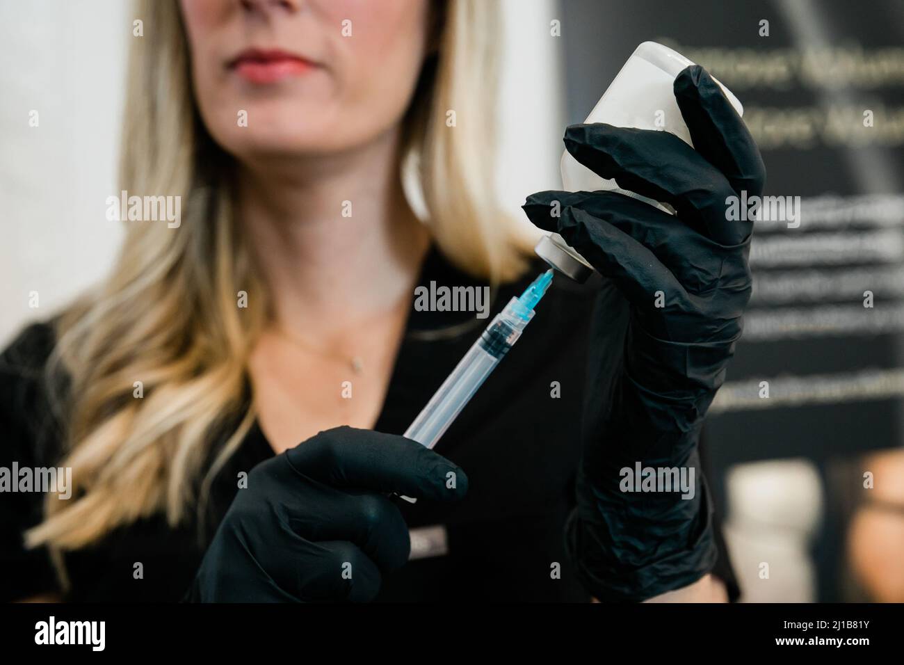 Close up of a medical provider wearing black scrubs and gloves filling ...
