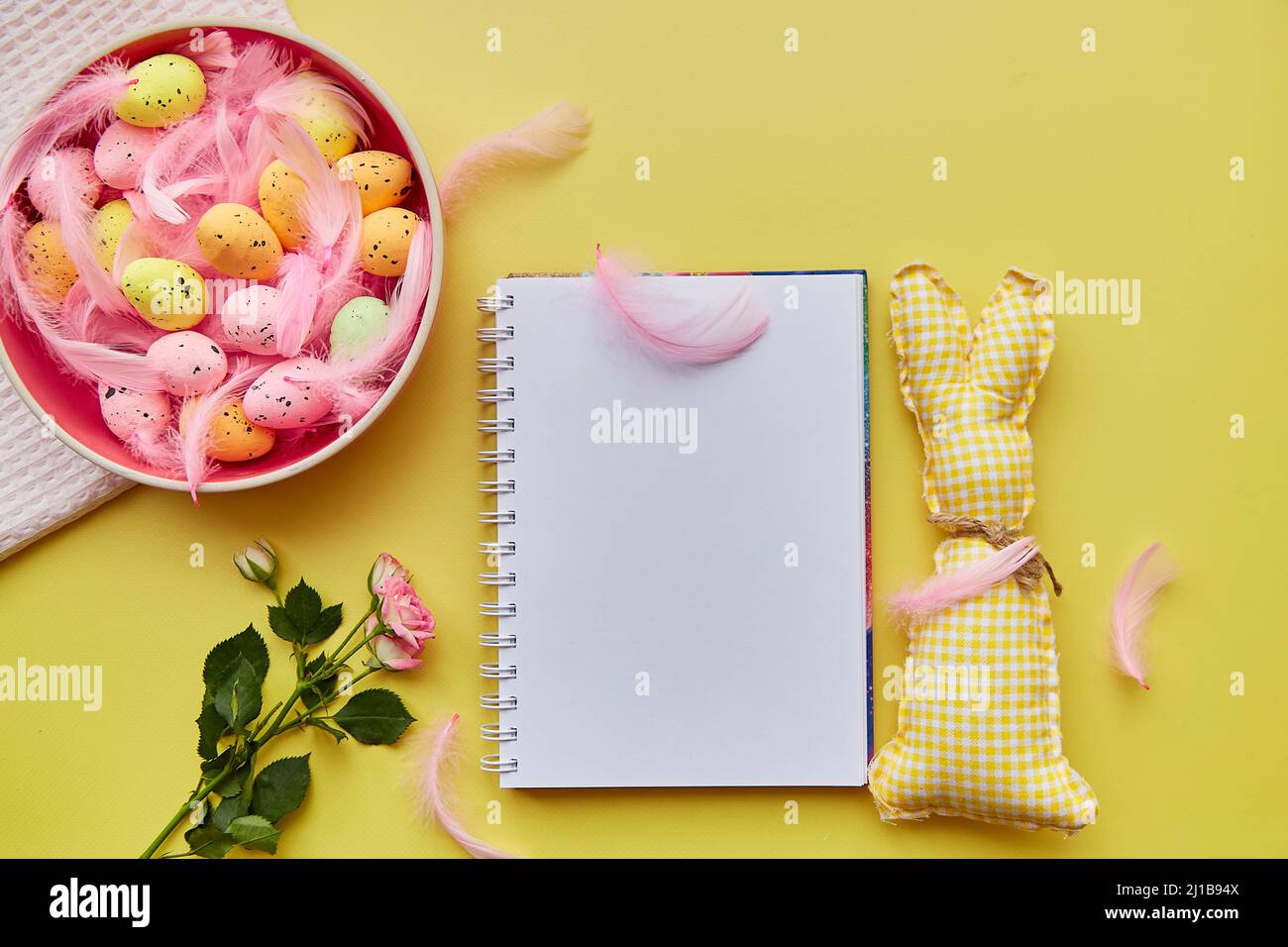 Easter mock up notepad. Pink bowl with colorful eggs, pink feathers ...