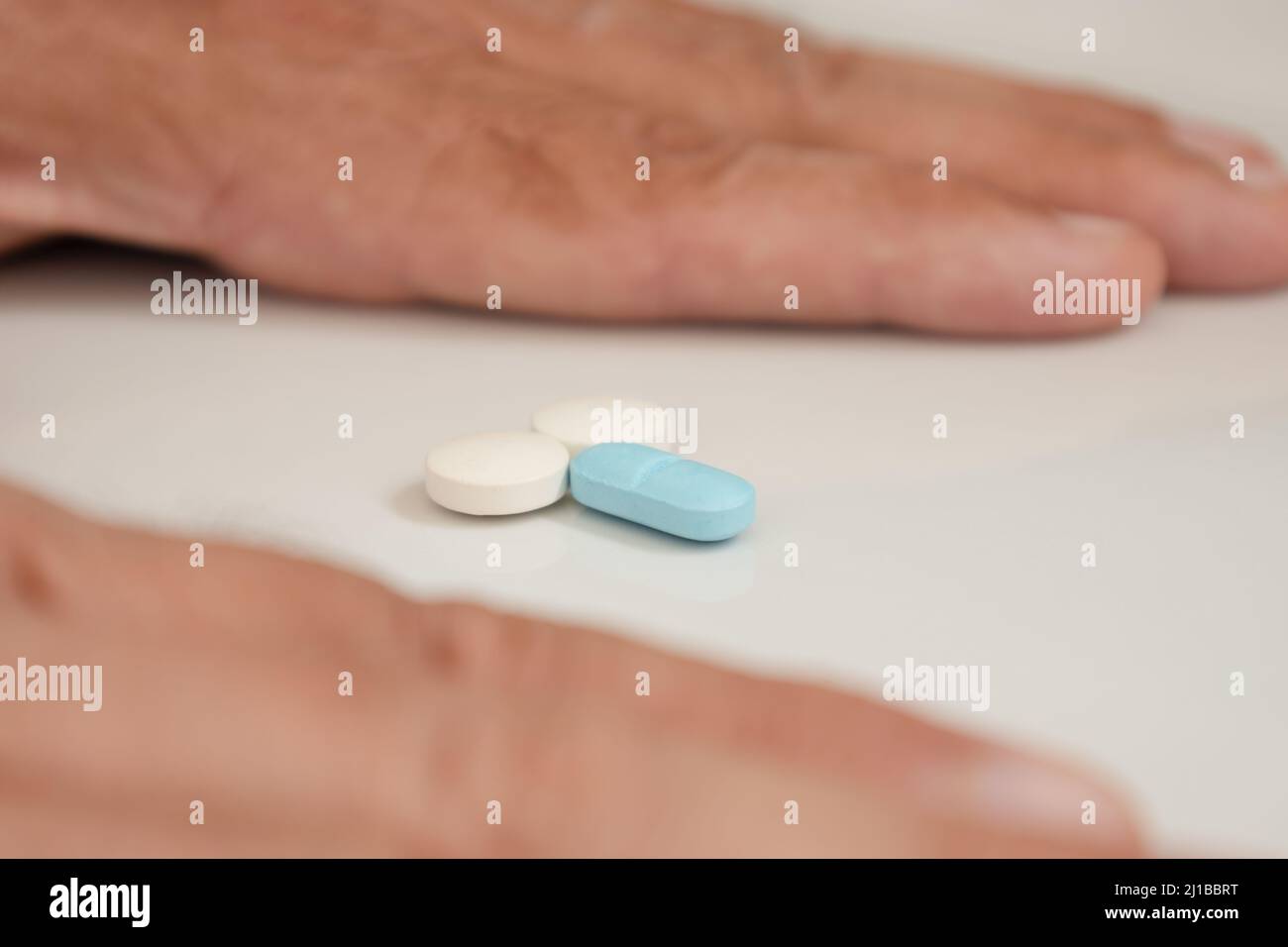 Colored pills forming small male genitalia in the hands of a man on a ...