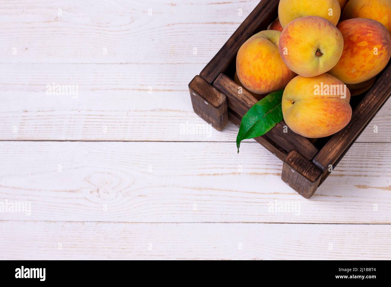 Wooden box with ripe peach on white wooden background. Flat lay, top ...
