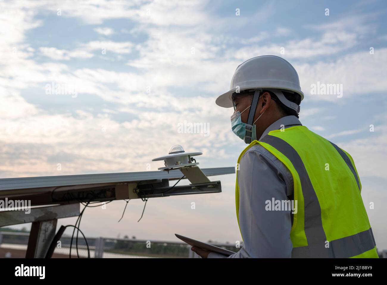 An engineer inspects a pyranometer installation in a solar farm to ...