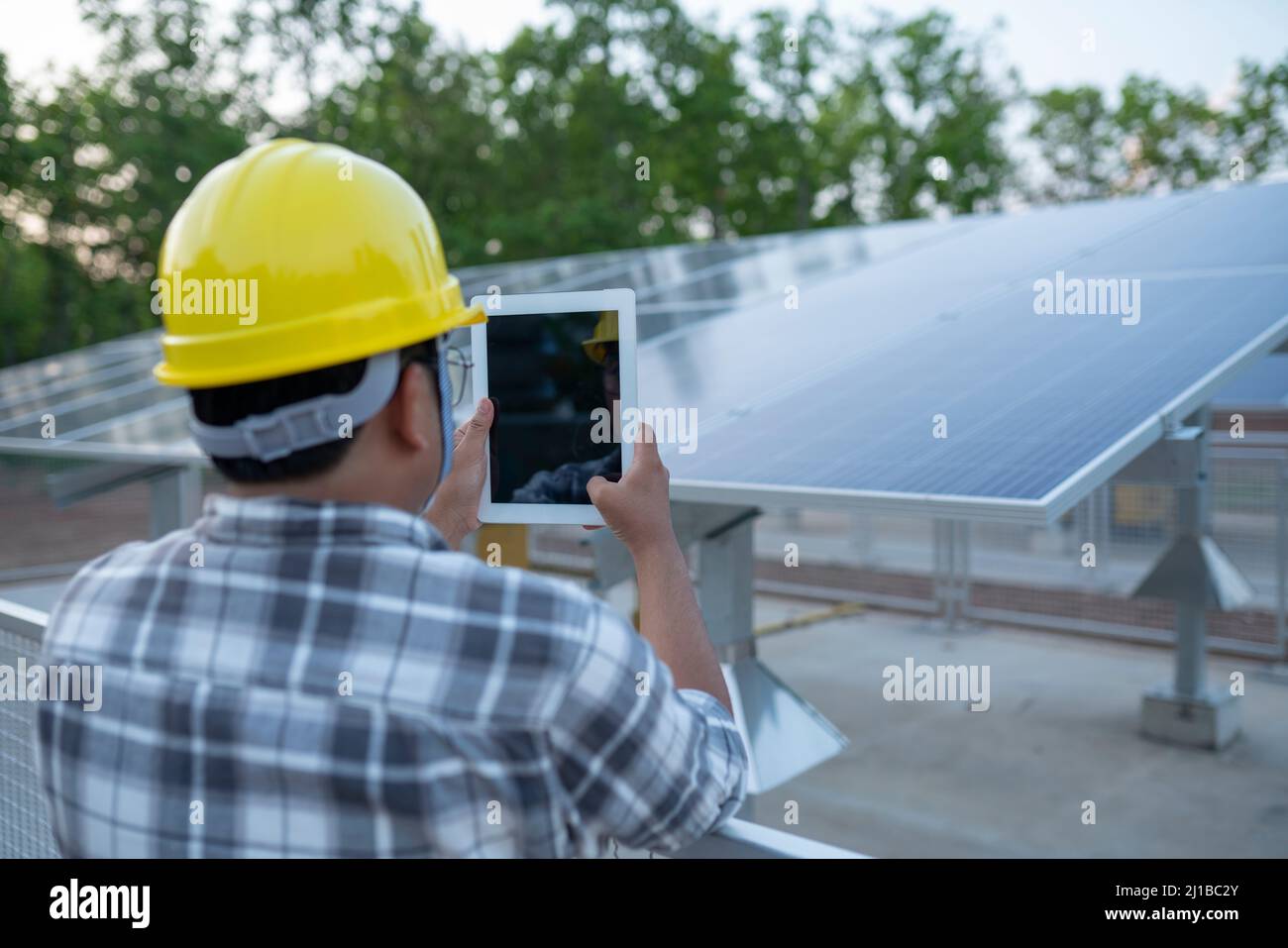 Young technicians use tablets to control solar panel power stations in ...