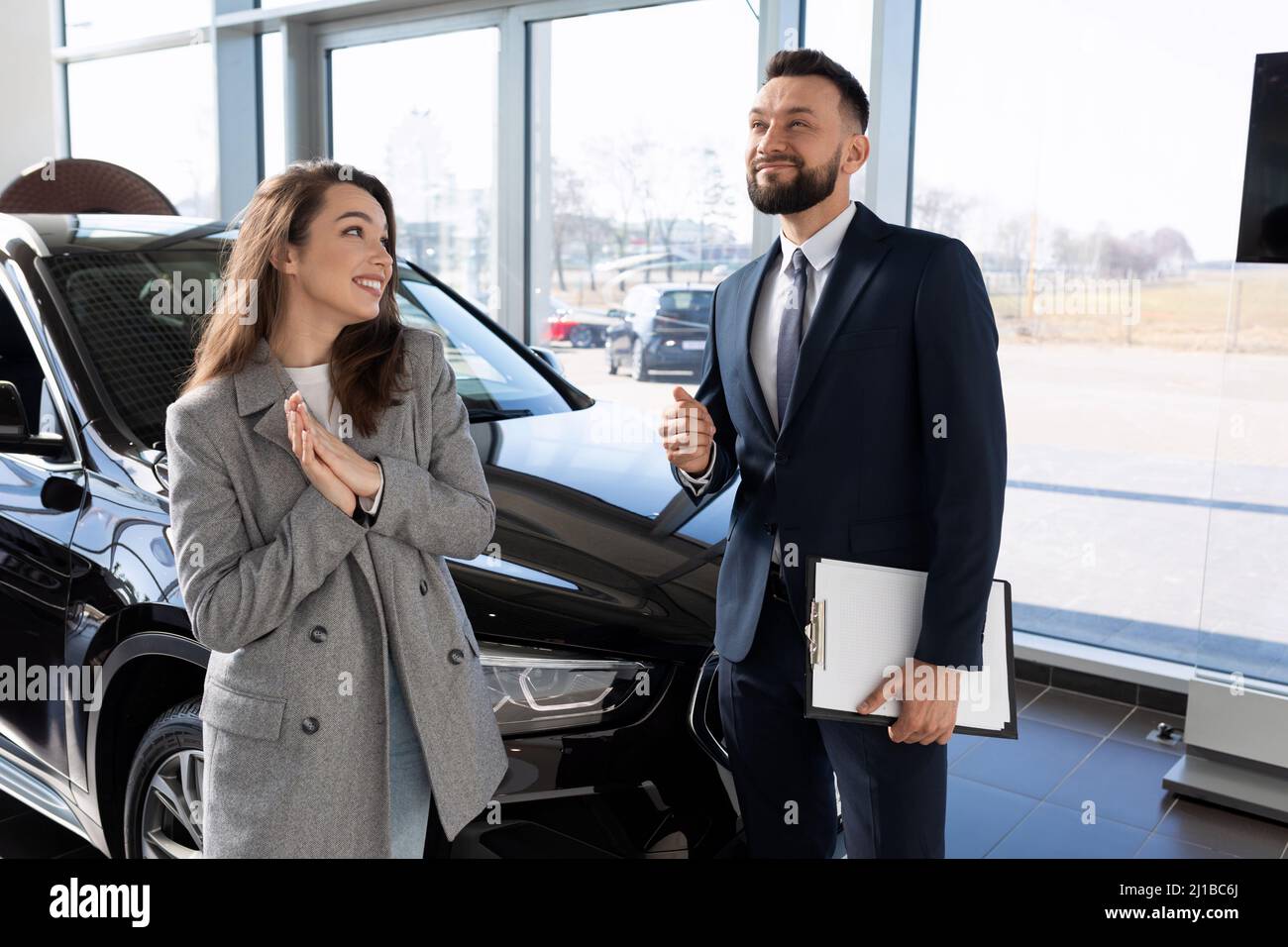 a woman buyer asks for a discount on a new car from an employee of the ...