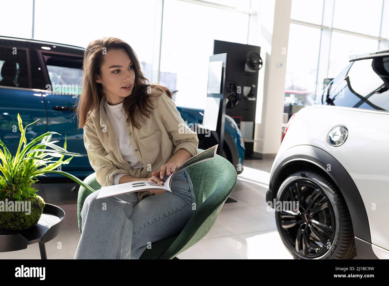 young woman studying the terms of insurance when buying a new car in a ...