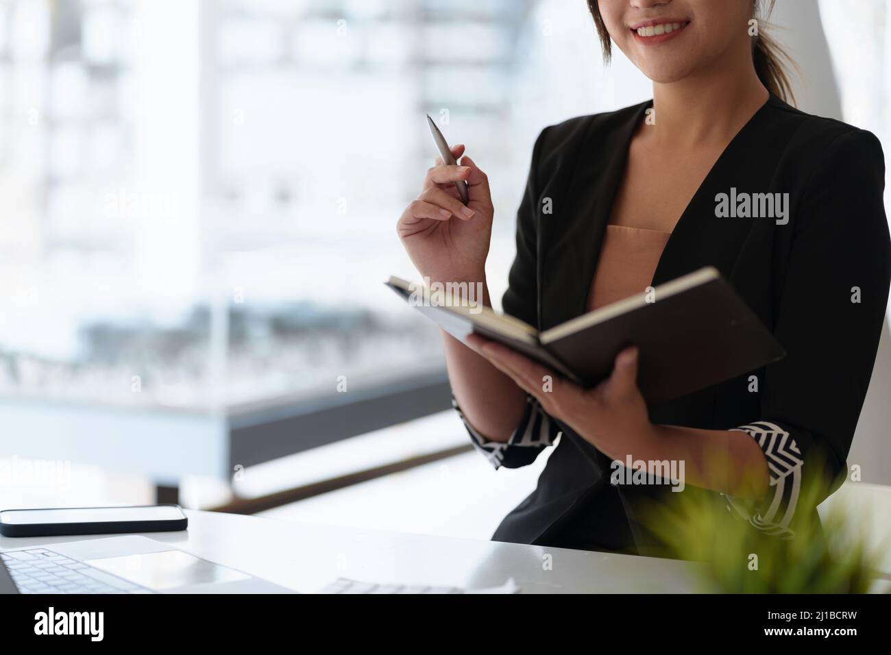Secretary checking schedule at front of boss room Stock Photo - Alamy