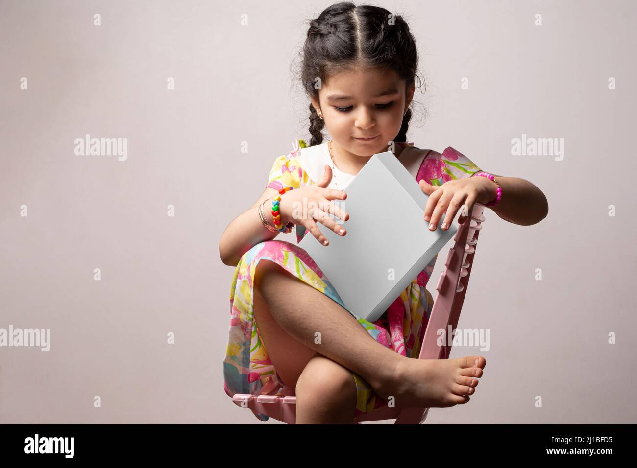 Little girl holding a hard box in hand, editable mock-up series ...