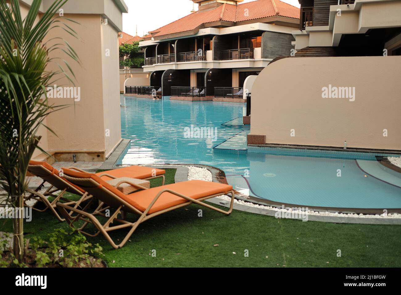 Two orange sun loungers stand by empty pool in evening after sunset ...