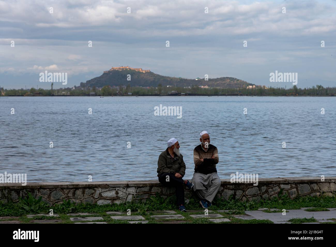 Elderly Kashmiri men talk on bank of dal lake during a cloudy spring ...