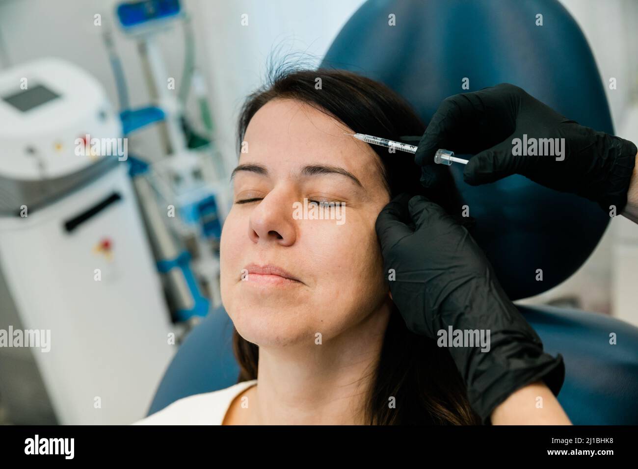 Close up of a woman getting botulinum toxin or fillers on her forehead ...