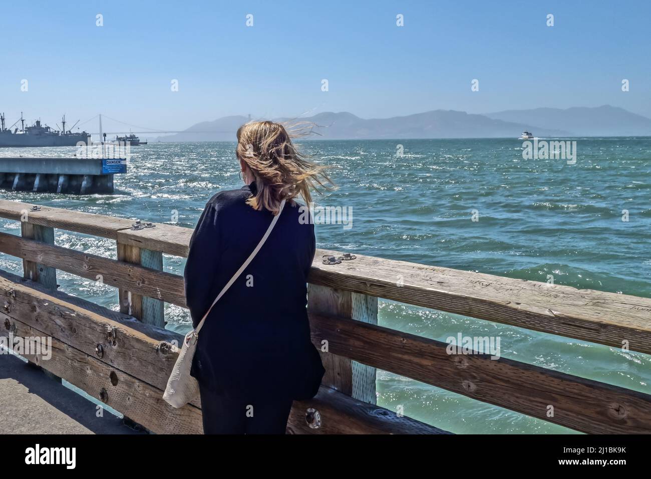 A rear view of a woman with hair blowing in the wind in San Francisco ...