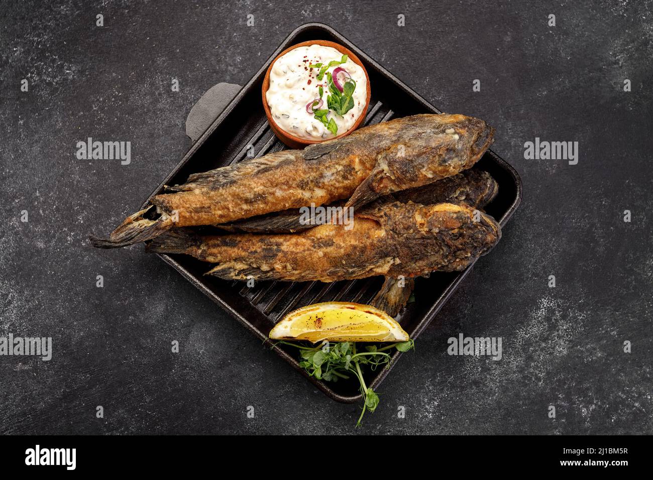 Fried fish Black Sea goby, with lemon and herbs, on a dark background ...