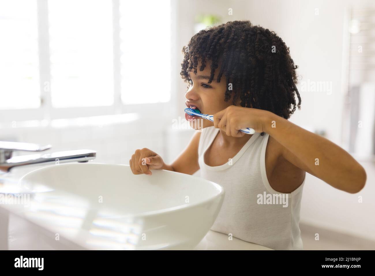 Cute hispanic boy brushing teeth by sink in bathroom at home Stock ...