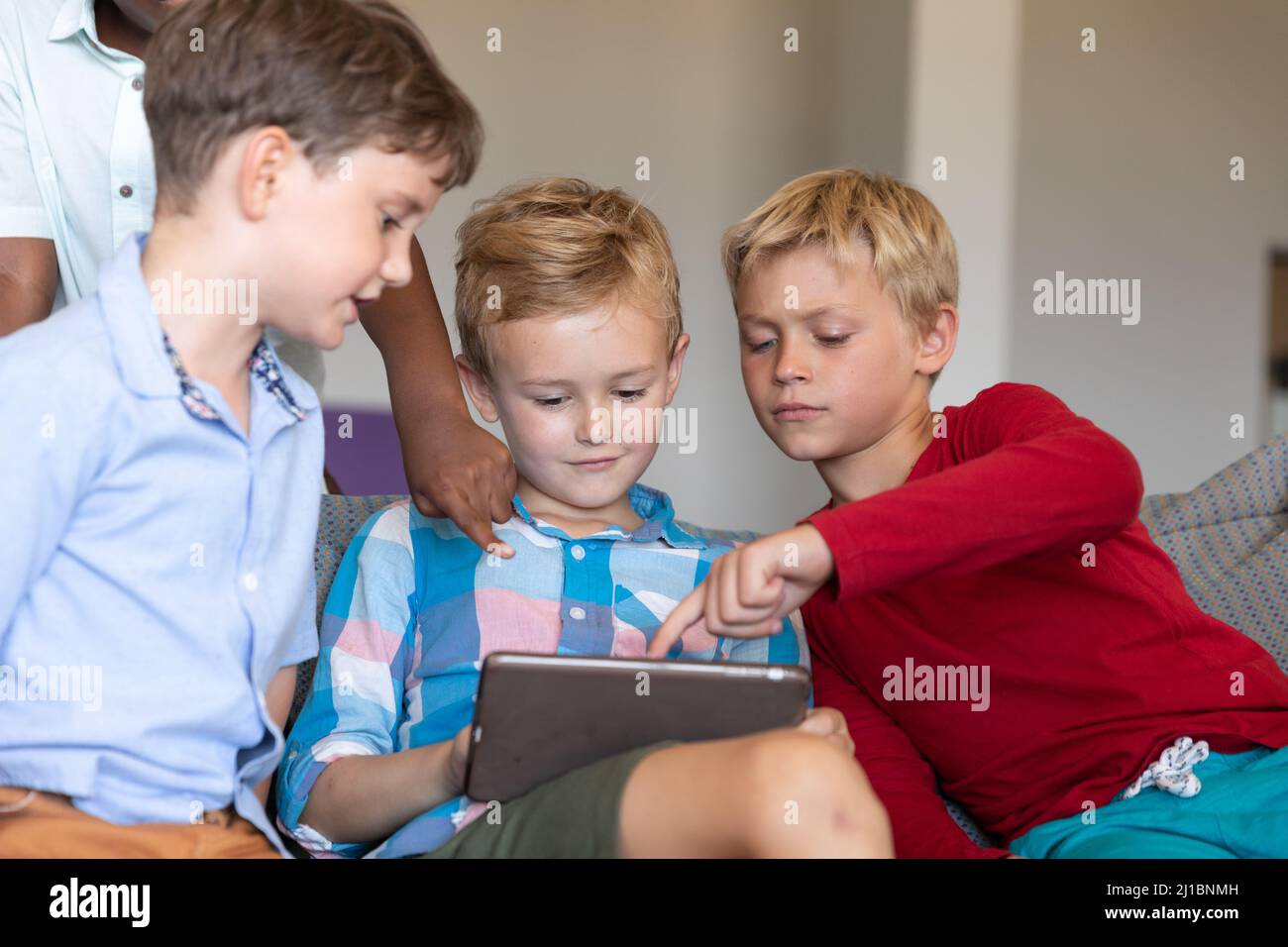 Multiracial elementary schoolboys using digital tablet while sitting on ...
