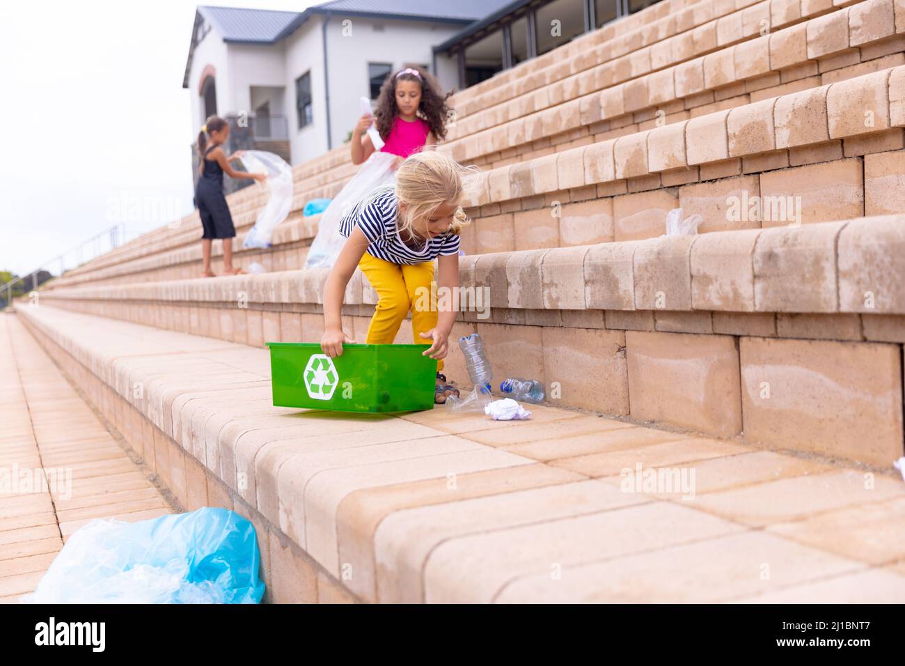 Multiracial elementary schoolgirls cleaning plastic waste on school ...