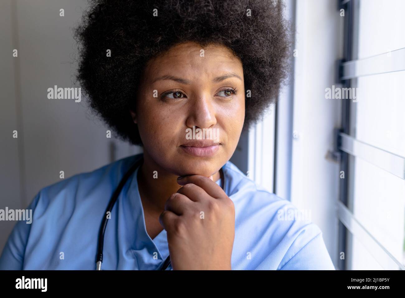 Close-up african american mid adult female nurse with hand on chin ... Close-up african american mid adult female nurse with hand on chin ...