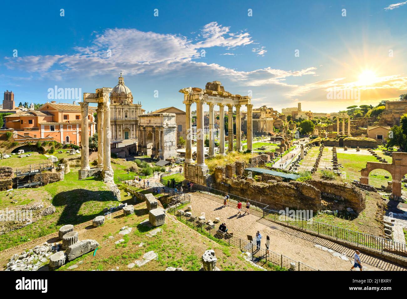 The ancient Roman Forum with the sun setting above the Colosseum in the ...