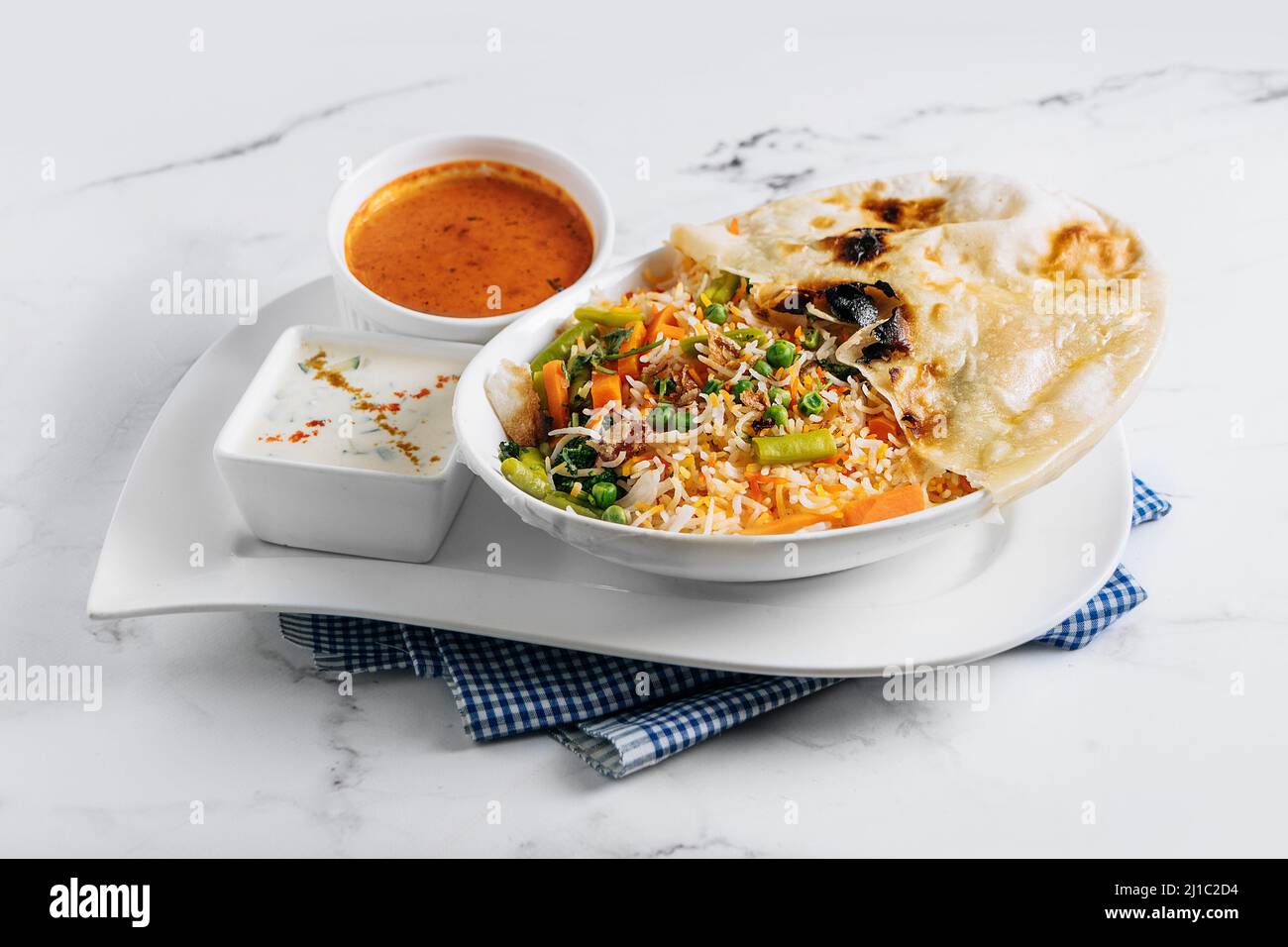 vegetable biryani with raita and sauce in a dish isolated on napkin ...
