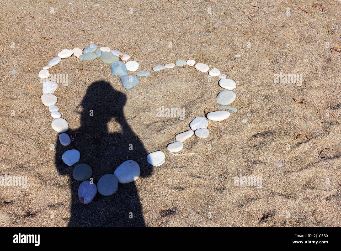A photographer is taking picture a pebble heart on the beach and ...