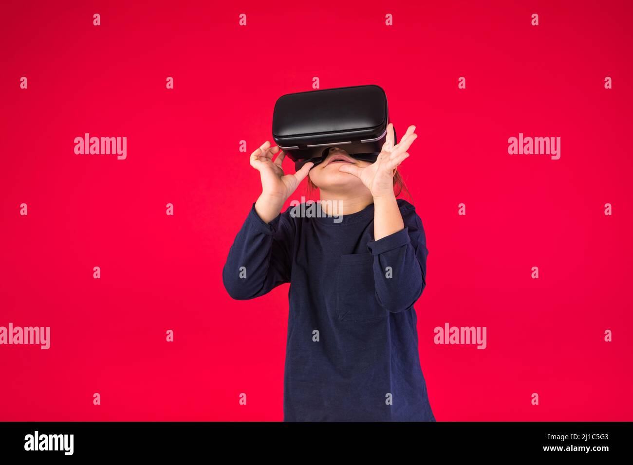Front view of little girl wearing virtual reality glasses amazed and ...