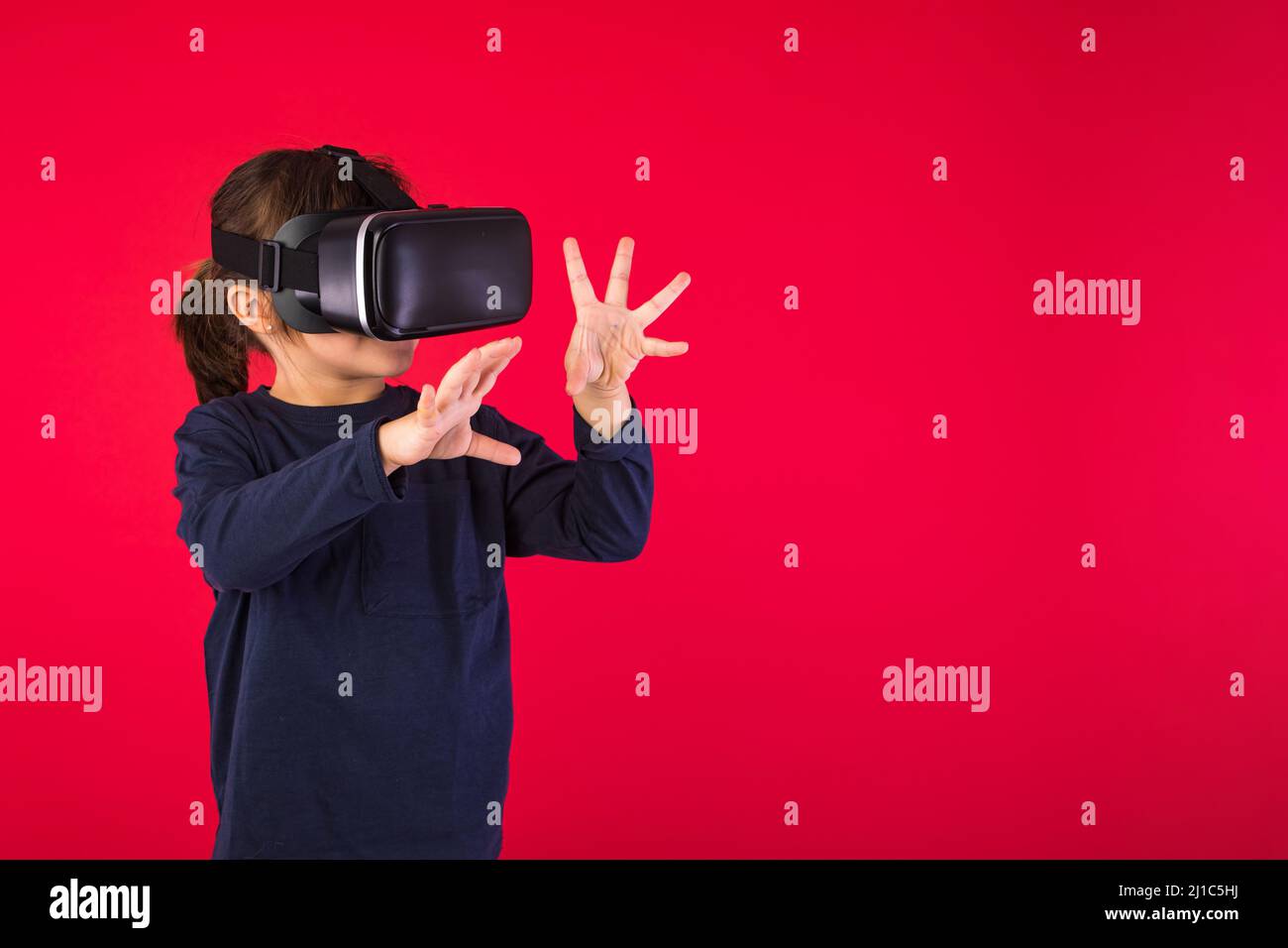 Side view of little girl wearing virtual reality goggles amazed and ...