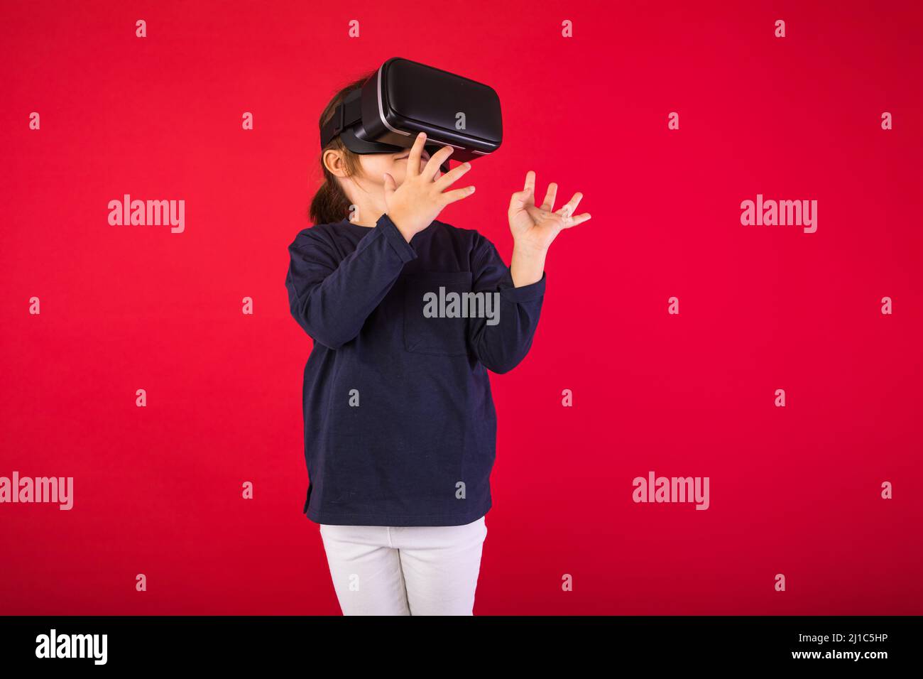 Side view of little girl wearing virtual reality goggles amazed and ...