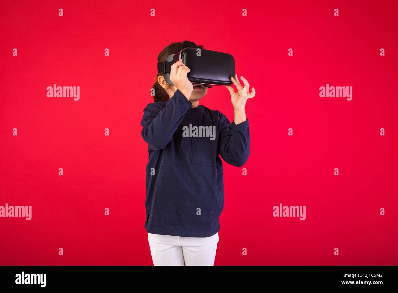 Front view of little girl wearing virtual reality glasses amazed and ...